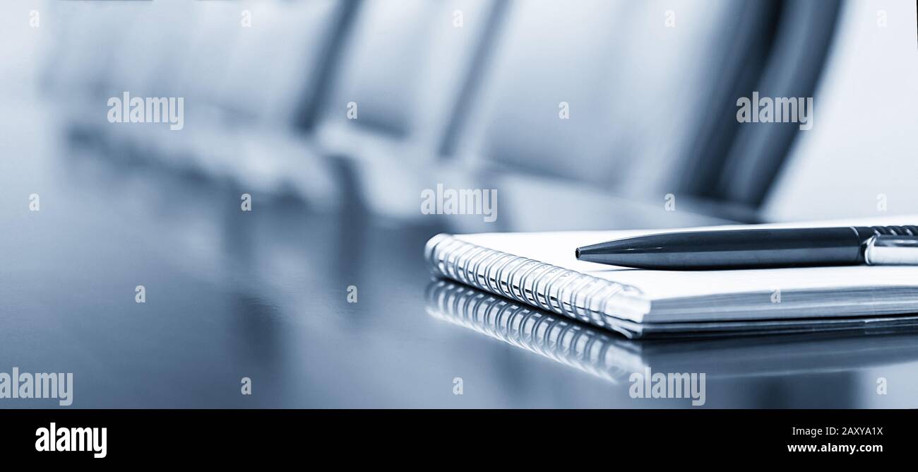 Closeup of notepad kept on table in empty conference room Stock Photo ...
