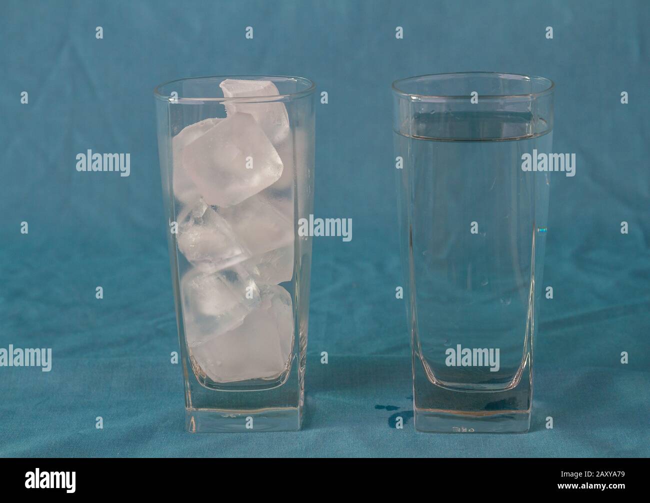 Melting ice concept - a glass full of ice next to a glass full of water ...