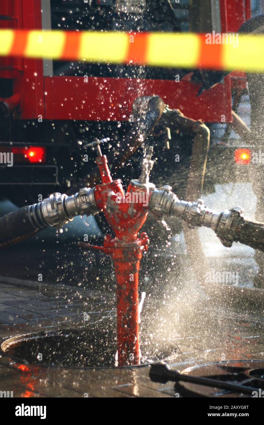 Water splashes from the fire hose and hydrant connections. Firefighters ...