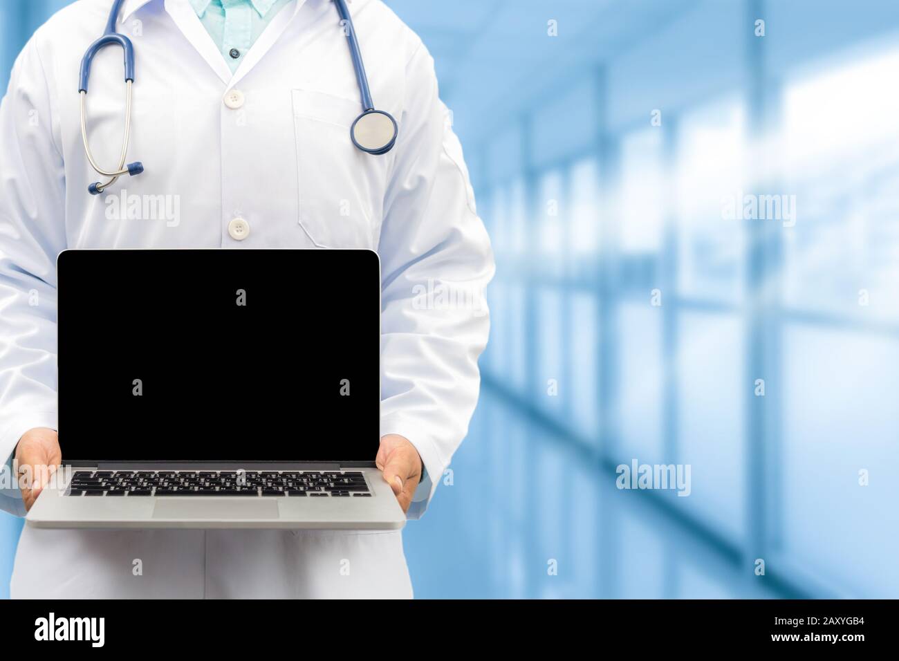Doctor holding laptop computer in straight front view with blurred ...
