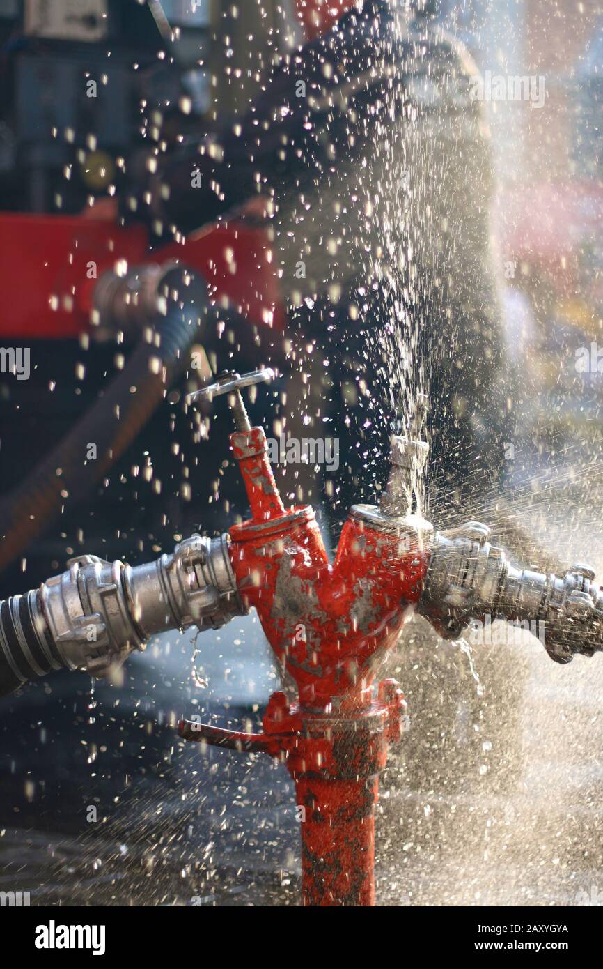 Water splashes from the fire hose and hydrant connections. Firefighters ...
