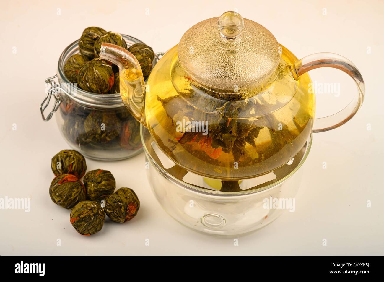 Flower tea brewed in a glass teapot, flower tea balls and a jar of tea ...