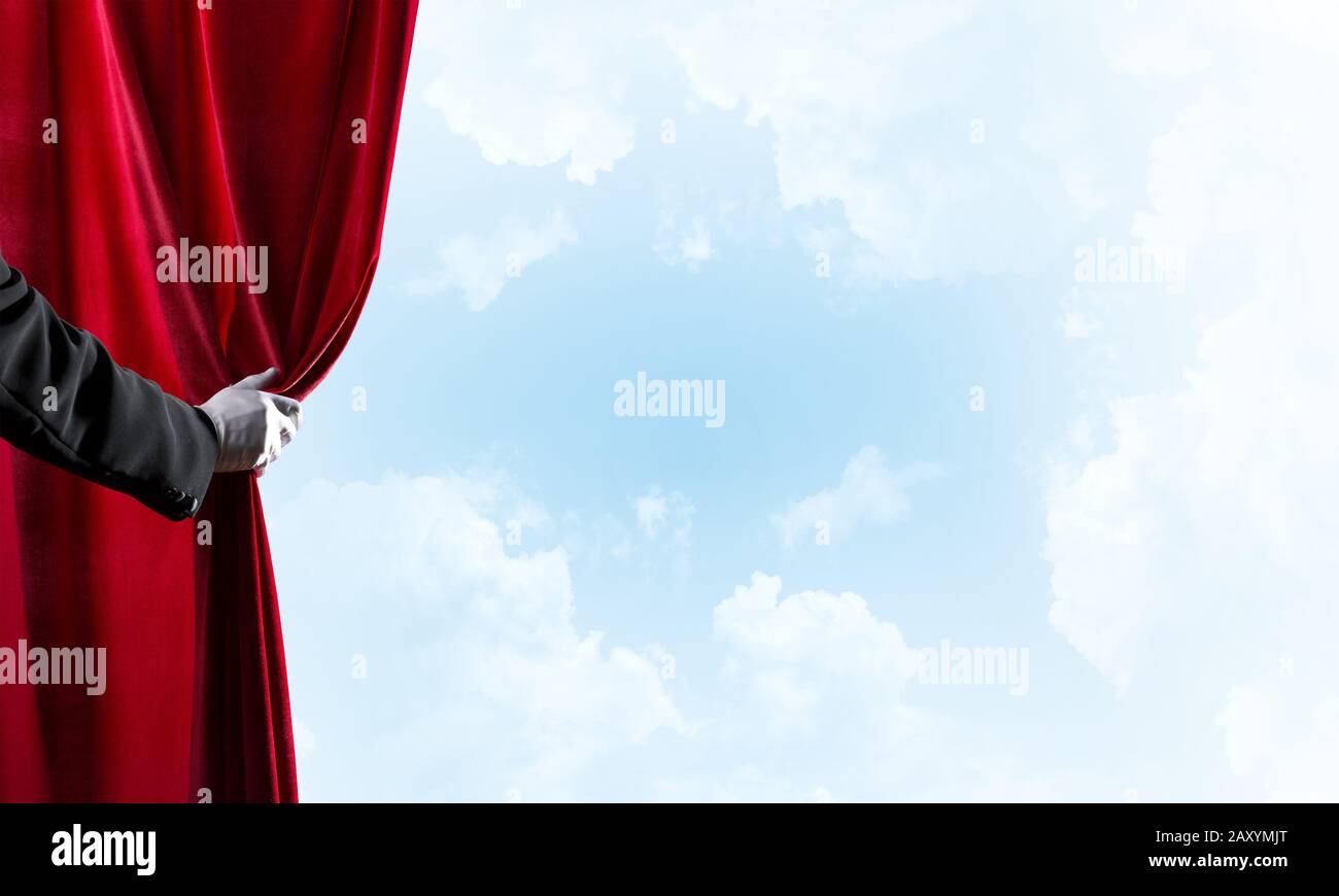 Cloudy landscape behind red curtain and hand holding it Stock Photo - Alamy