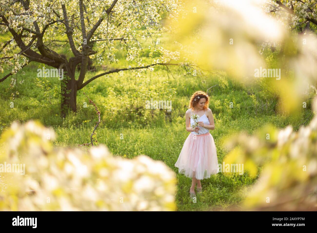 Young attractive girl walks in spring green park enjoying flowering ...