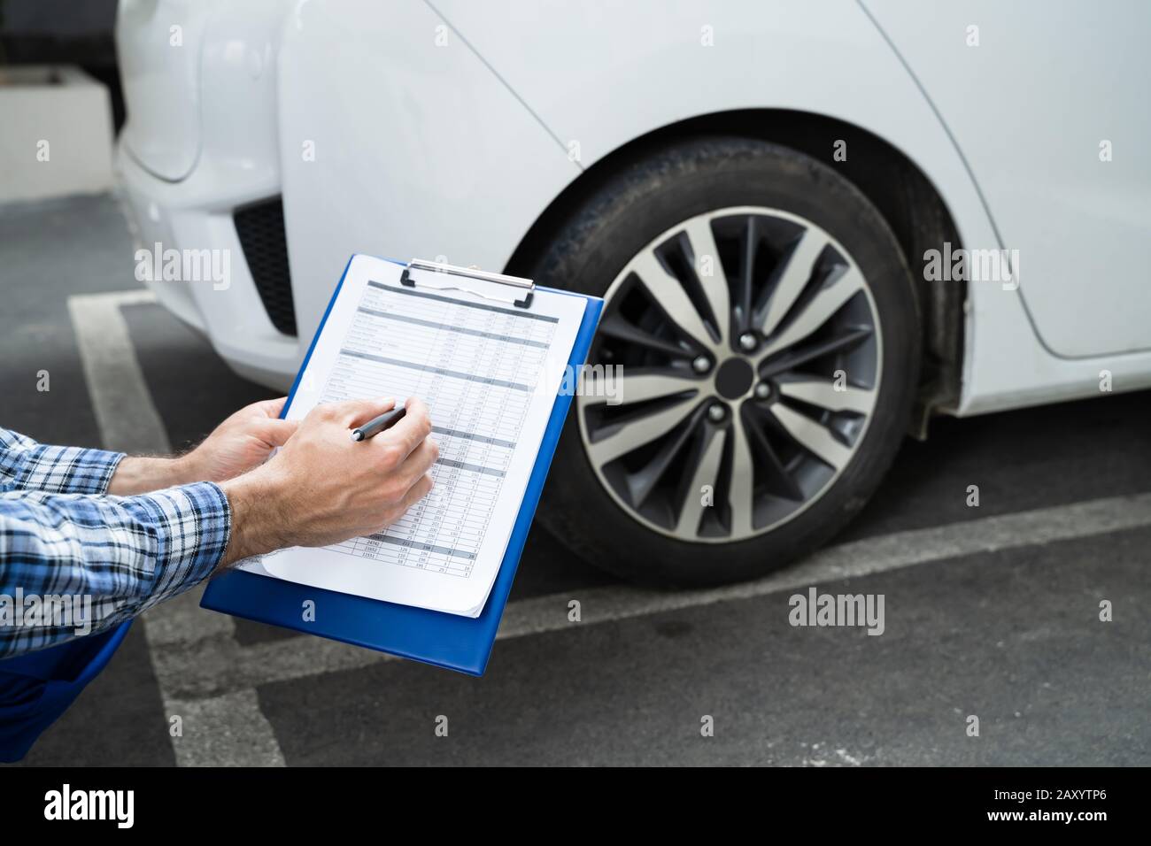Young Mechanic Writing On Clipboard White Examining Car Wheel Stock ...