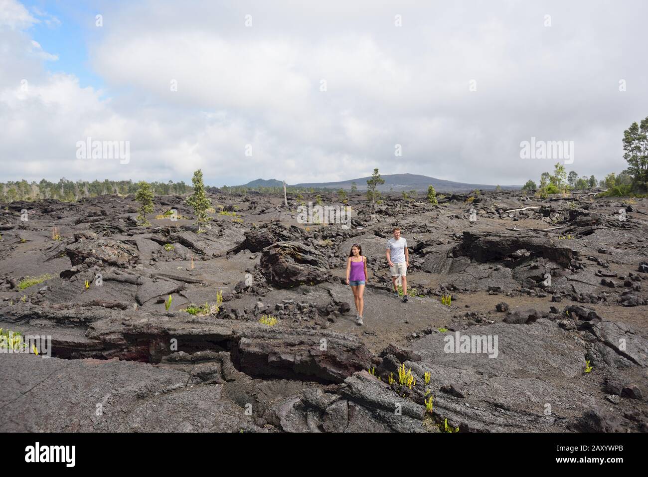 Hawaii destination travelers couple hiking in volcanic rocks on Kilauea ...