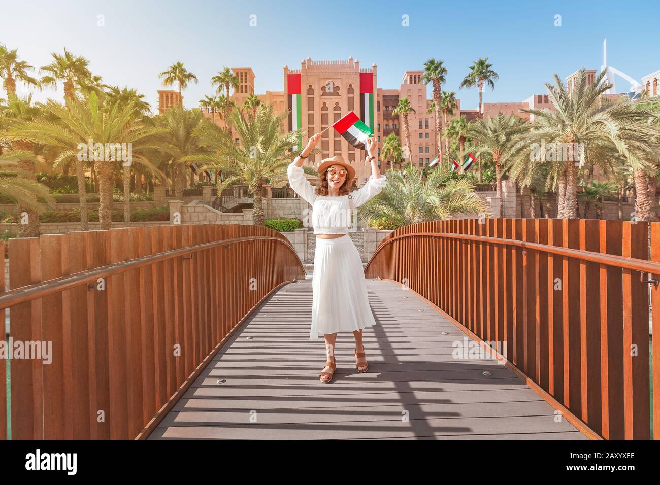 happy girl holding UAE flag and admires beautiful view of the Madinat ...