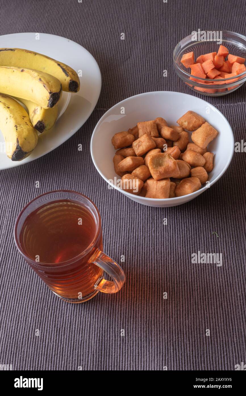 a vertical view of a cup of black tea next with small bowl of small ...