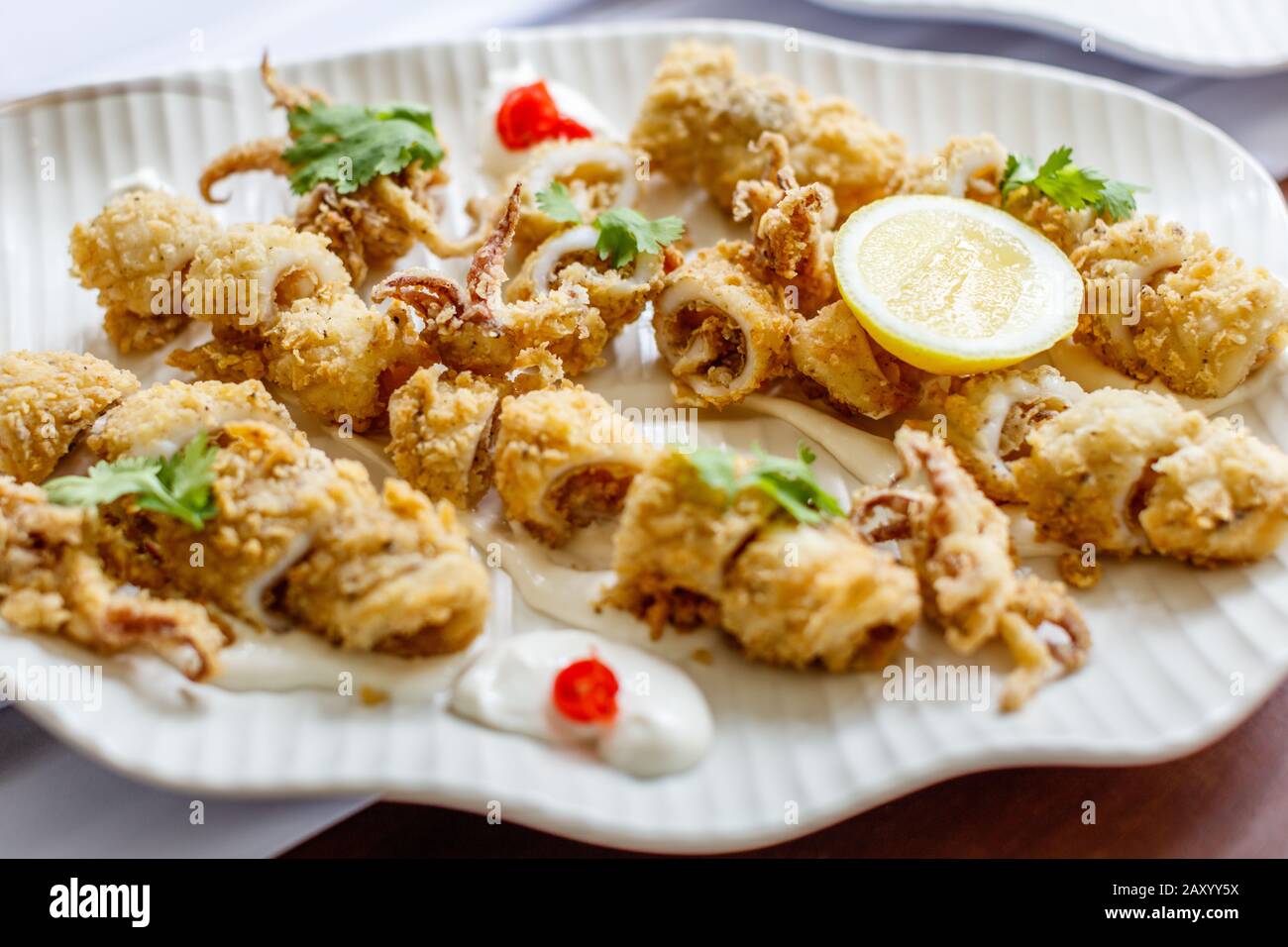 Deep-fried battered cut calamari with tar-tar sauce and lemon. served ...