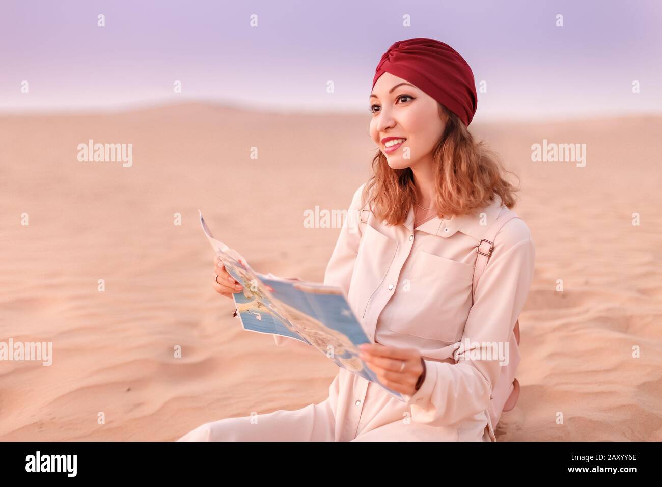 Asian woman wearing turban reading map in Sahara desert in Africa ...