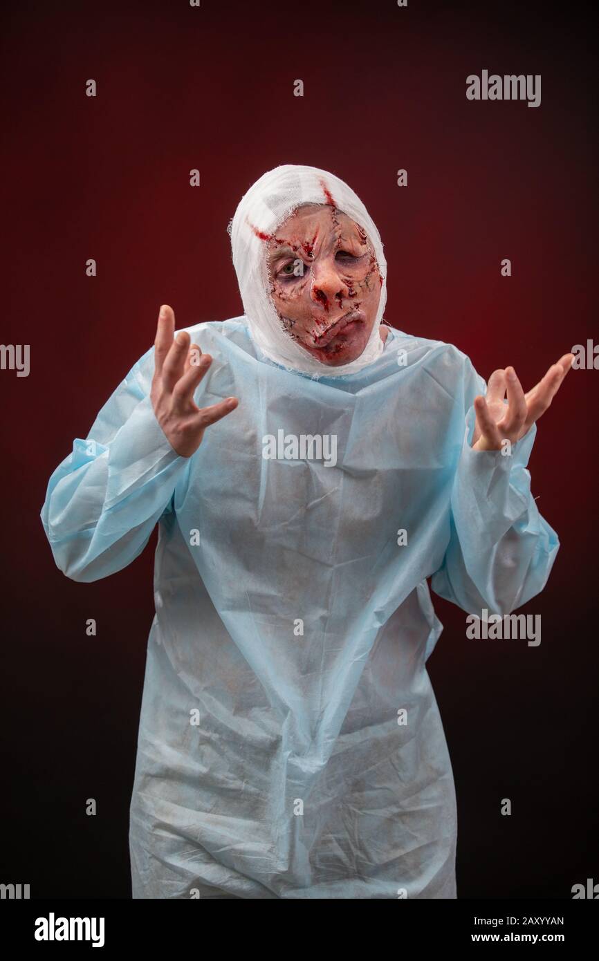 Crazy zombie horror make up. Person in blue madical shirt and bandaged ...