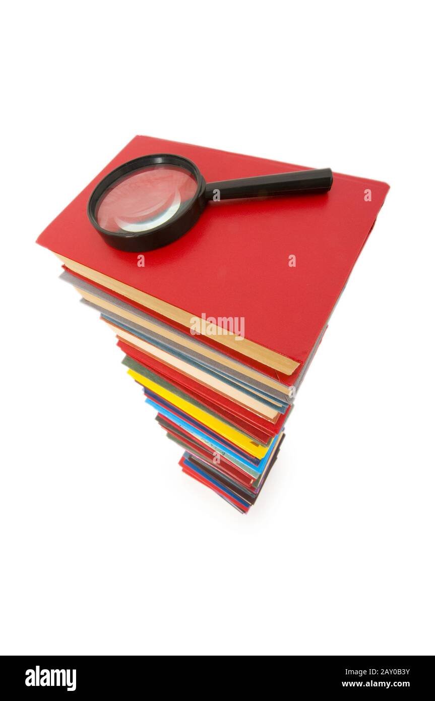 Magnifying glass over the stack of books Stock Photo - Alamy