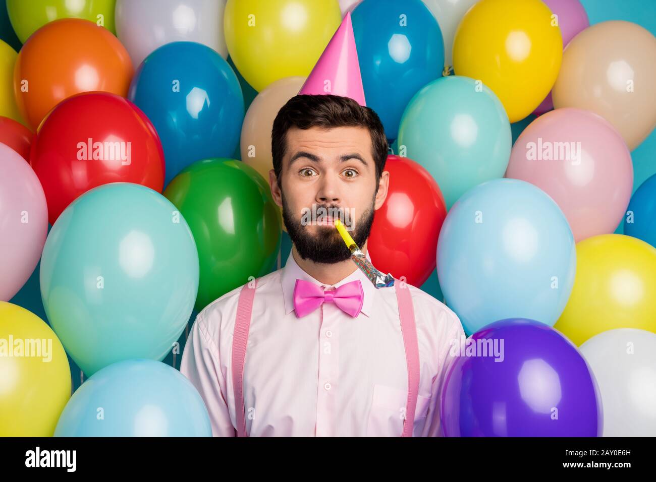 Photo of funny handsome guy different colors noisemaker in mouth ...
