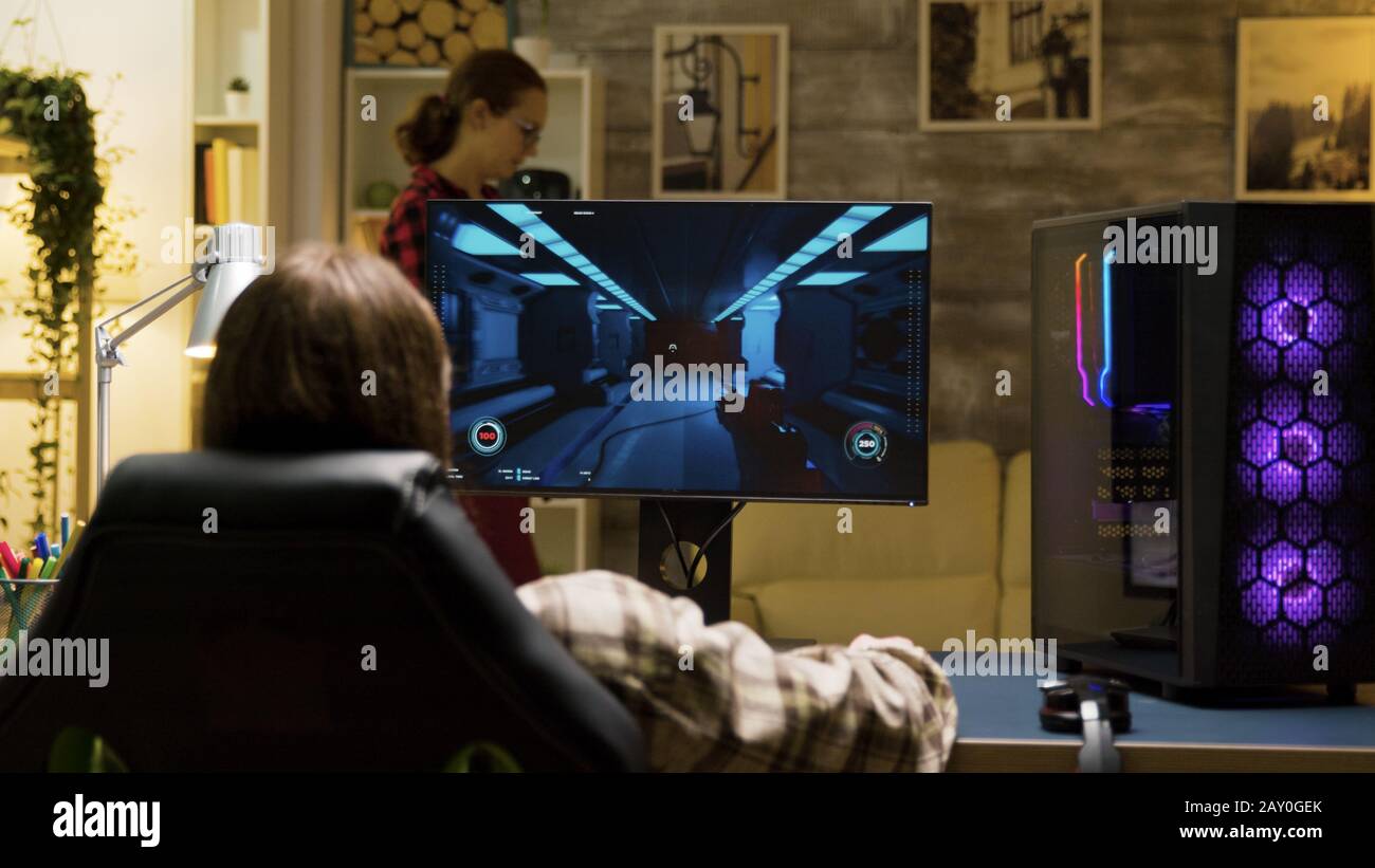 Back view of man sitting on gaming chair and playing games on computer ...