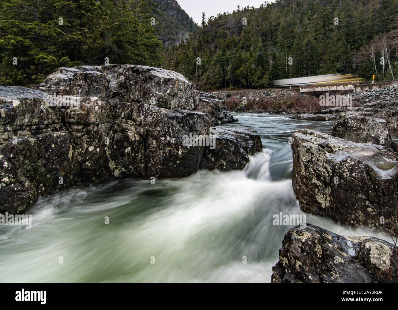 River running through a rural landscape with train driving past ...