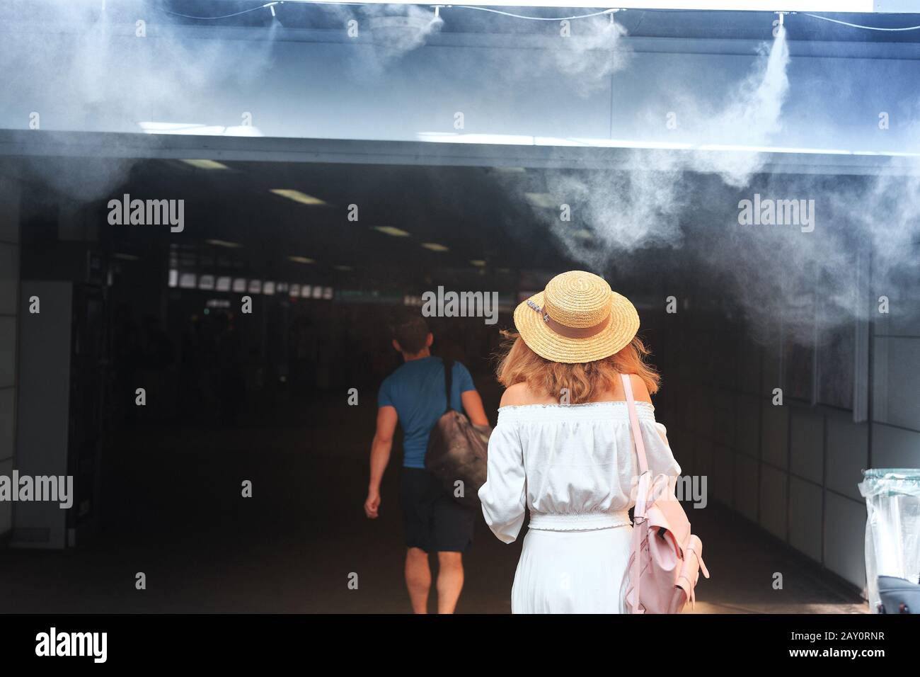 People enjoy a cold water spray at hot summer day near the metro ...