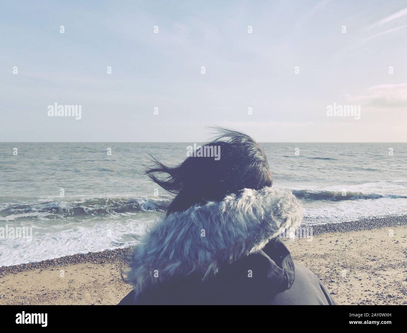 Windswept woman standing on beach in winter, Aldeburgh, Suffolk ...