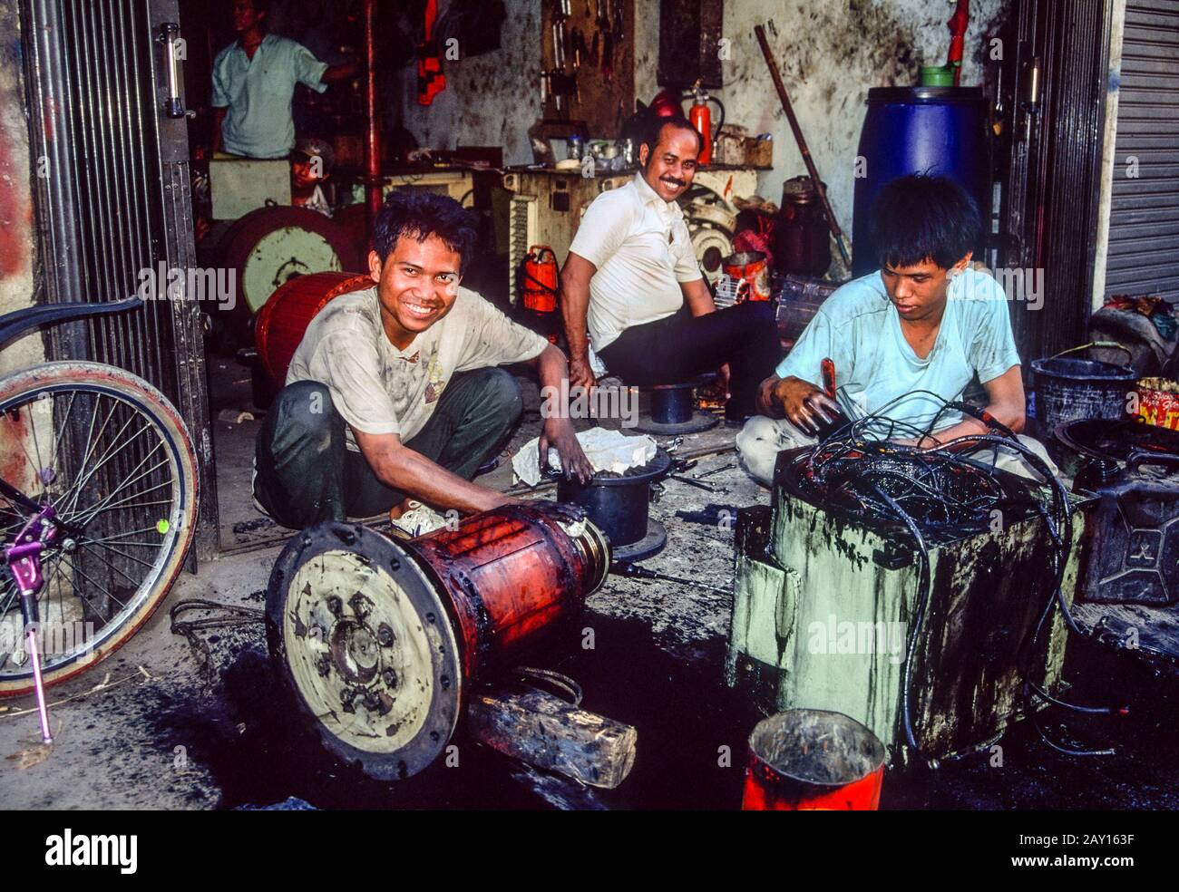 Back street workshop with grimy mechanics at work, Jakarta, Indonesia ...
