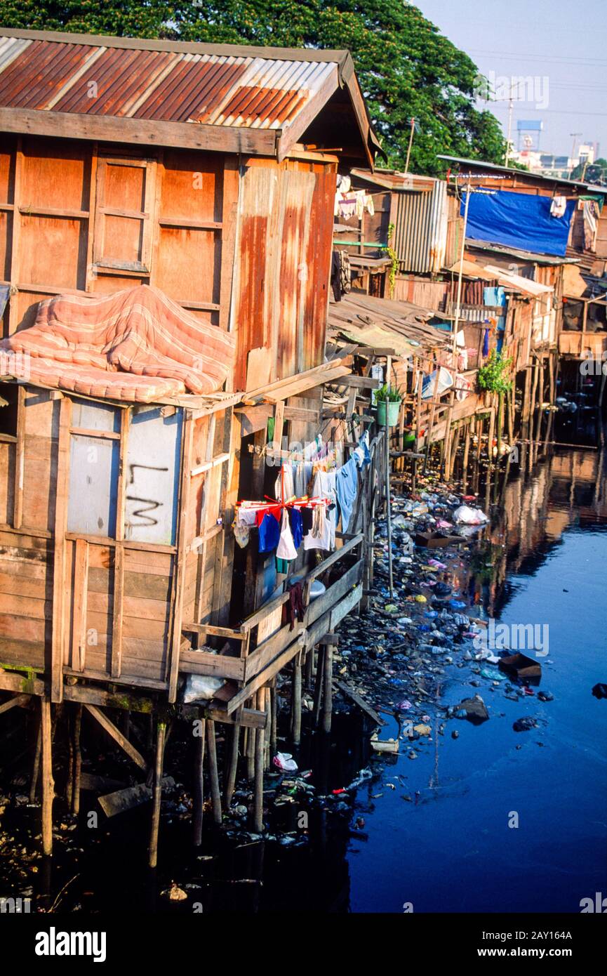 Riverside slum homes made up of shacks along a canal strewn with ...