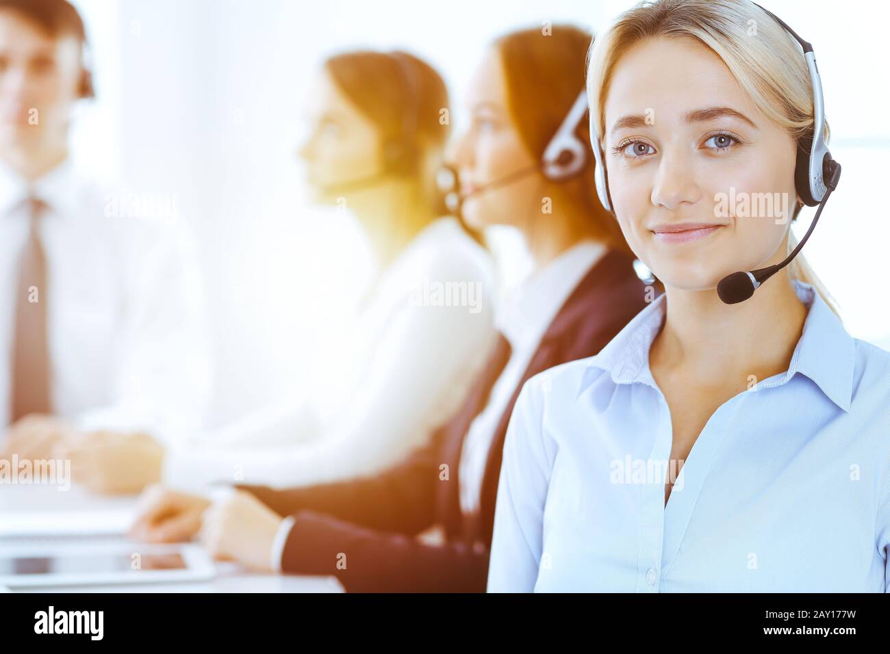 Group of diverse phone operators at work in sunny office. Handsome ...