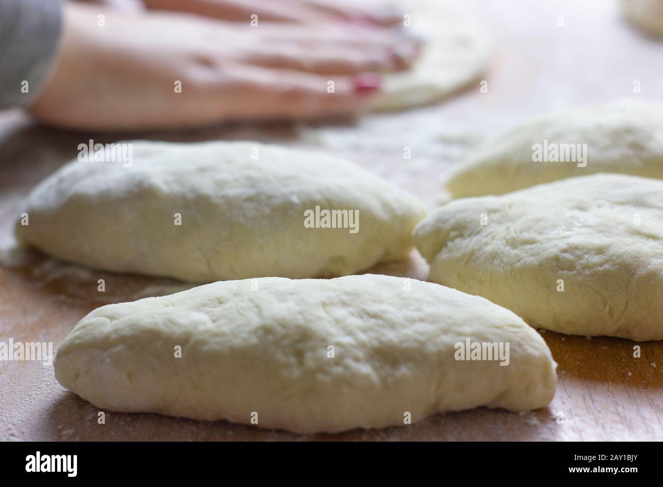 Raw pies for baking in the oven on the background of the female hands ...