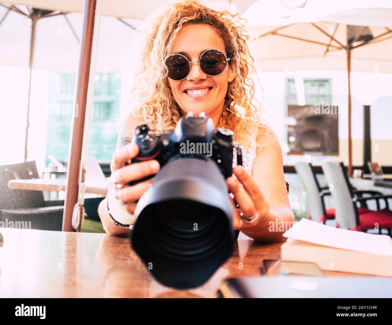 Cheerful beautiful woman with modern big professional reflex camera ...