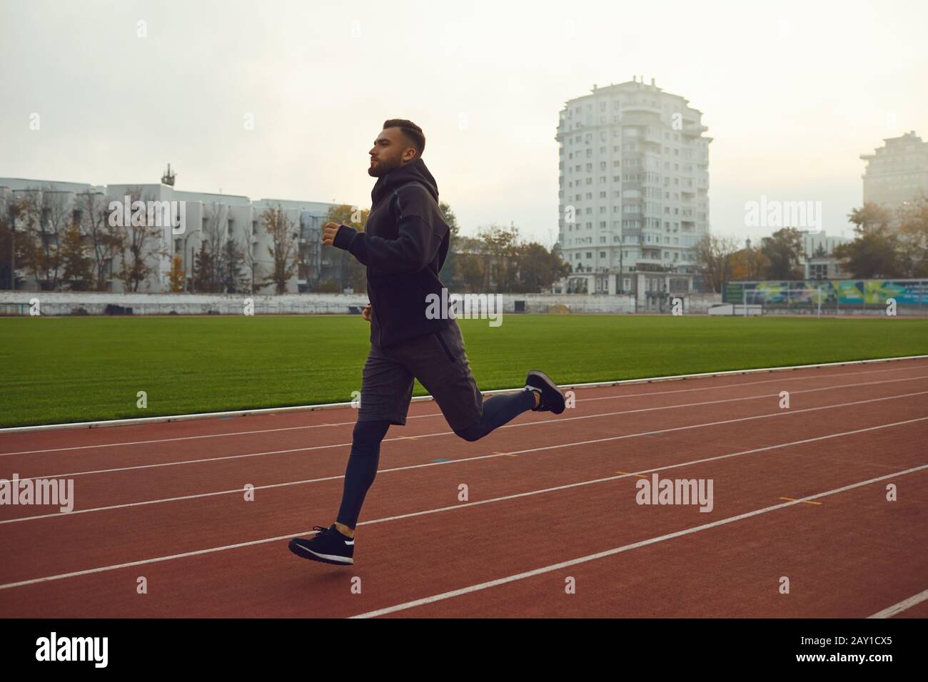 A young athlete runs on a stadium in the fog Stock Photo - Alamy