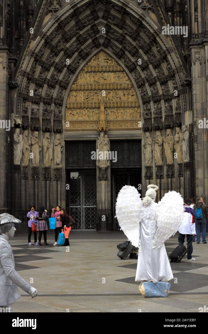 Angel as living statue in front of Cologne Cathedral Stock Photo - Alamy