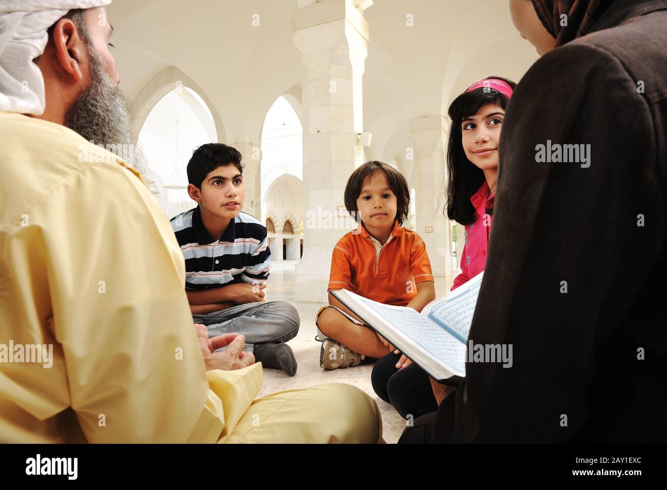 Islamic education inside white mosque, teacher and children learning ...