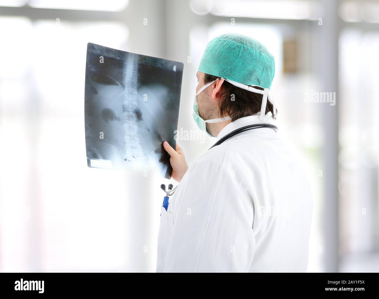 Medical doctor analysing x-ray image handheld, standing at office desk ...