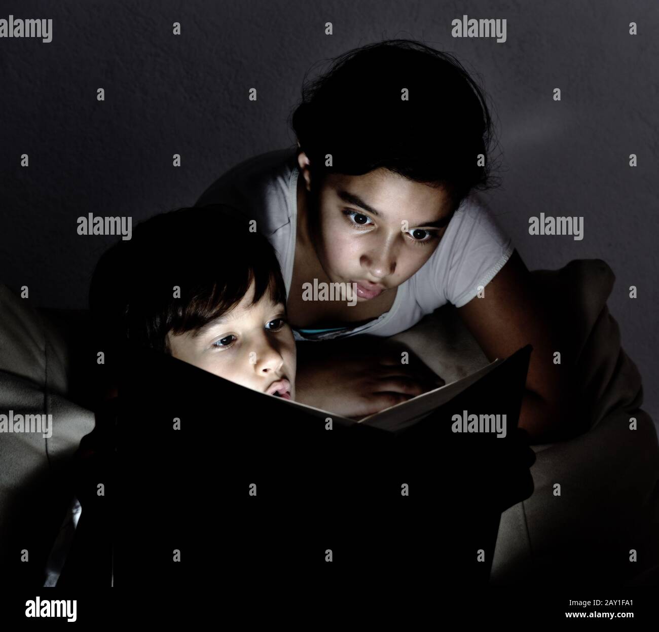 Cute kids reading a book at night Stock Photo - Alamy