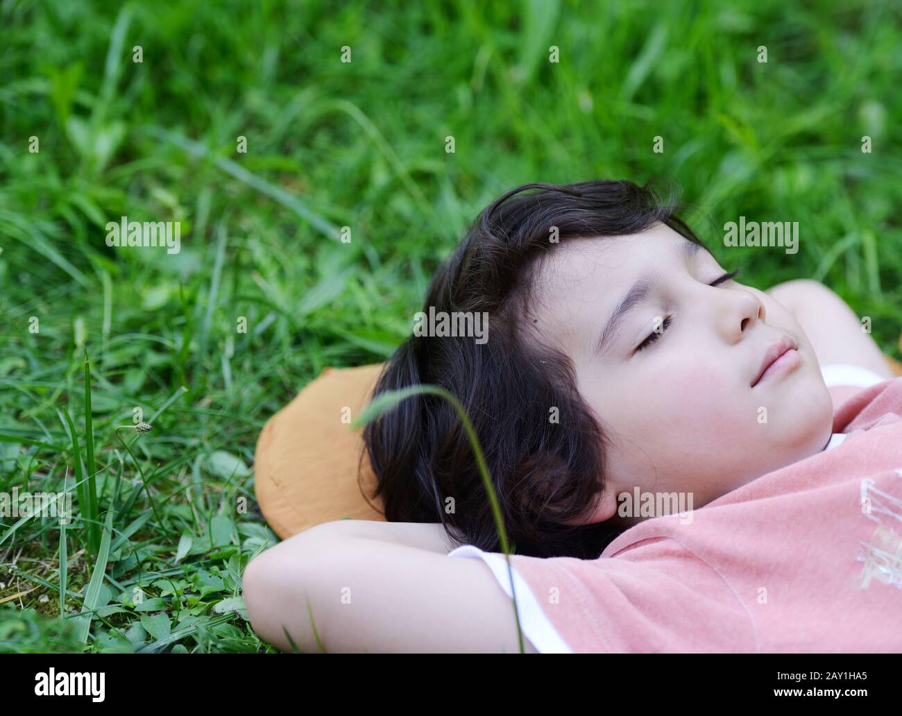 Closeup portrait of a little happy boy sleeping on grass in nature and ...