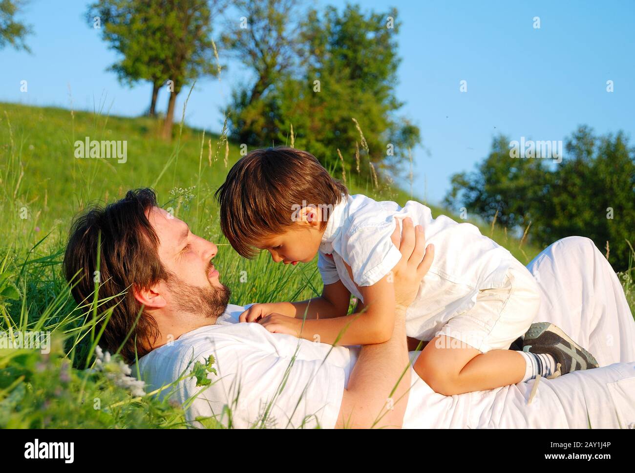 Young father in white with child on beautiful meadow Stock Photo - Alamy