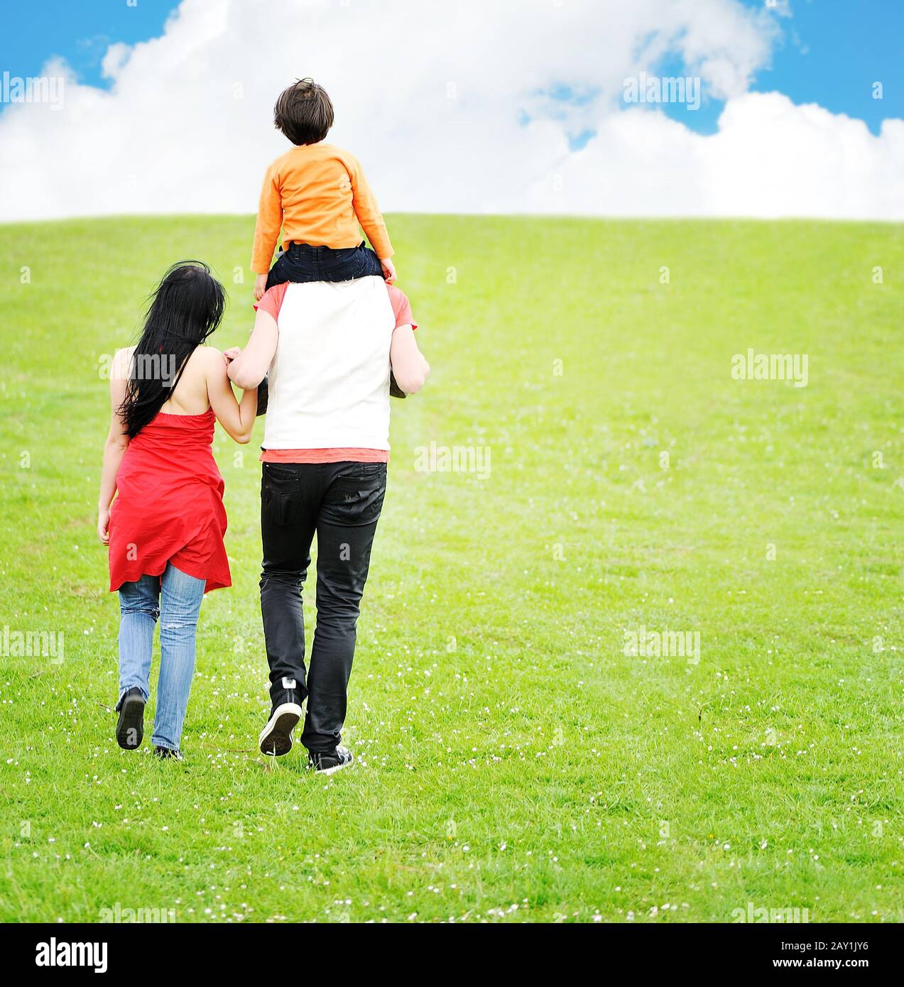 Young family having a walk in the sun over the meadow on a bright ...