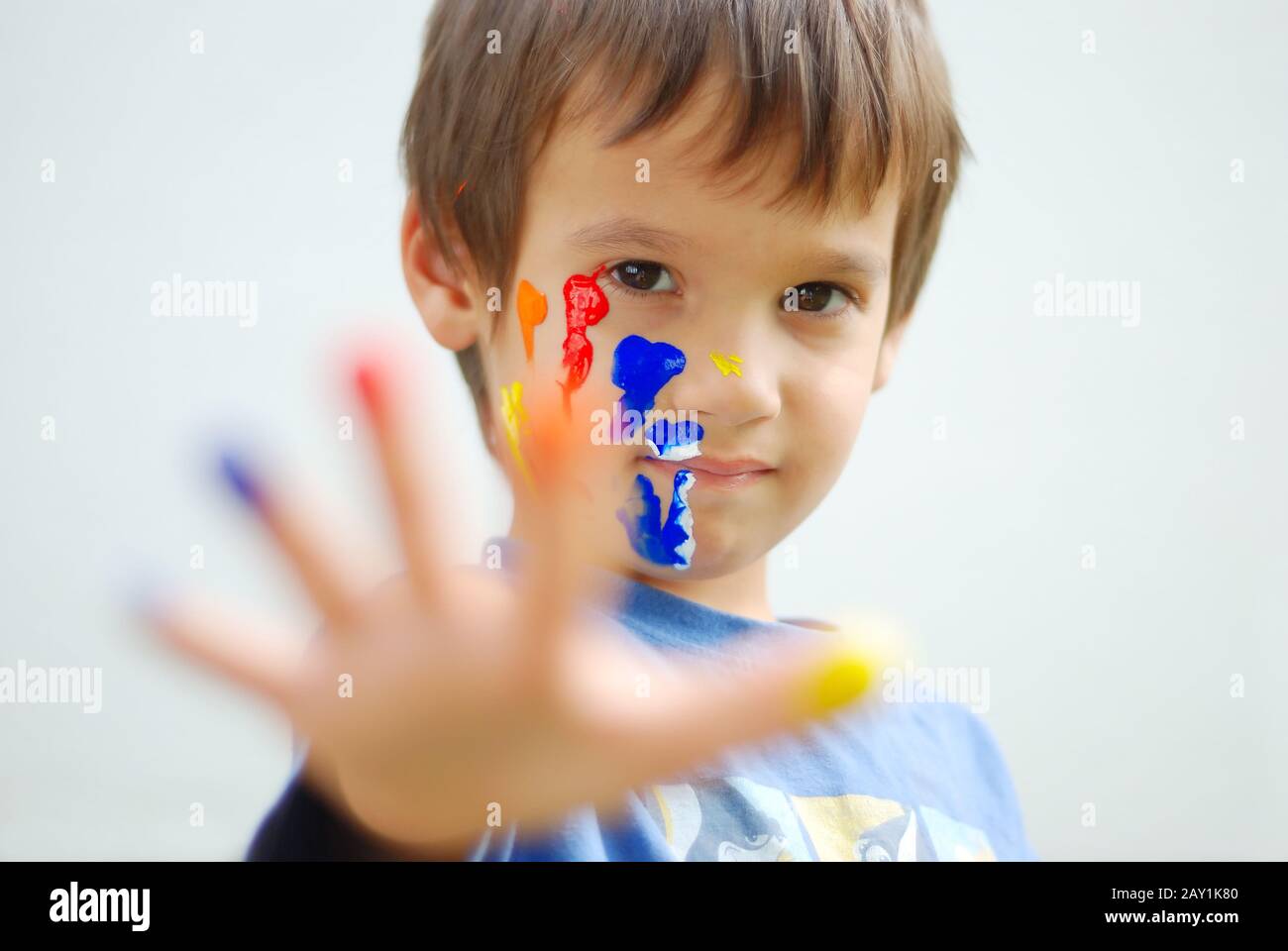Kid with color on his fingers and face looking Stock Photo - Alamy