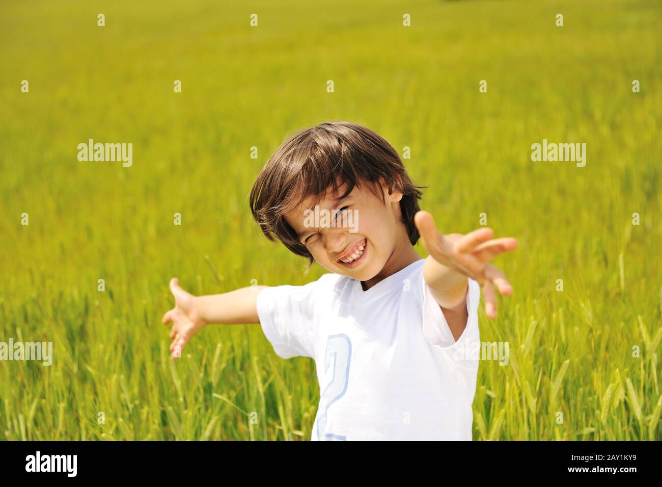 Happy kid on green field with widely opened arms Stock Photo - Alamy