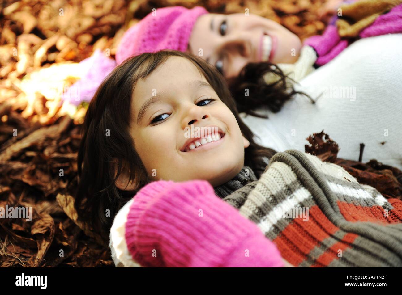 Little happy positive kid laying on fall ground with his mother, yellow ...