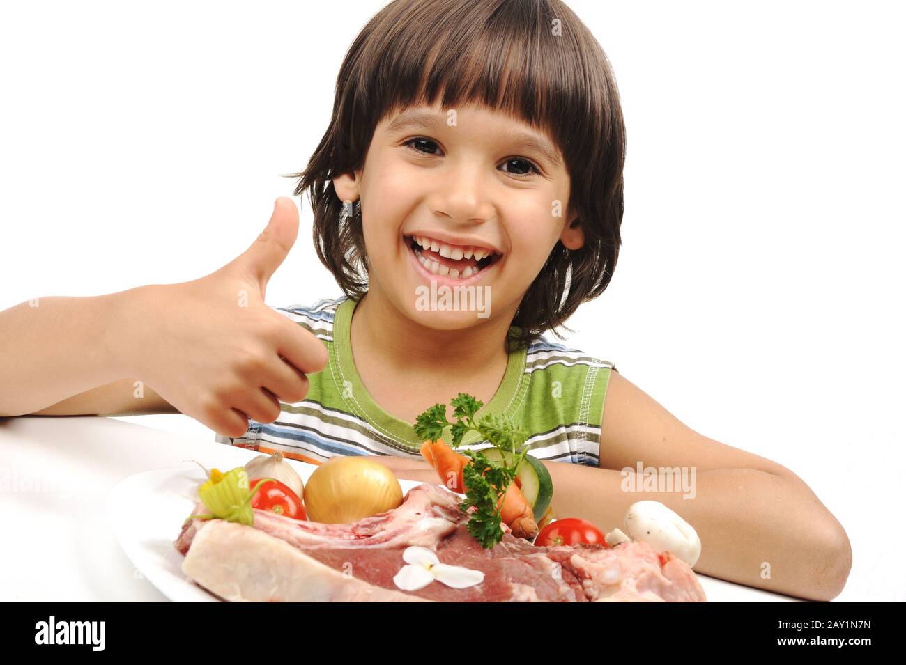 Cute positive boy and raw meat and vegetables in plate reading for ...