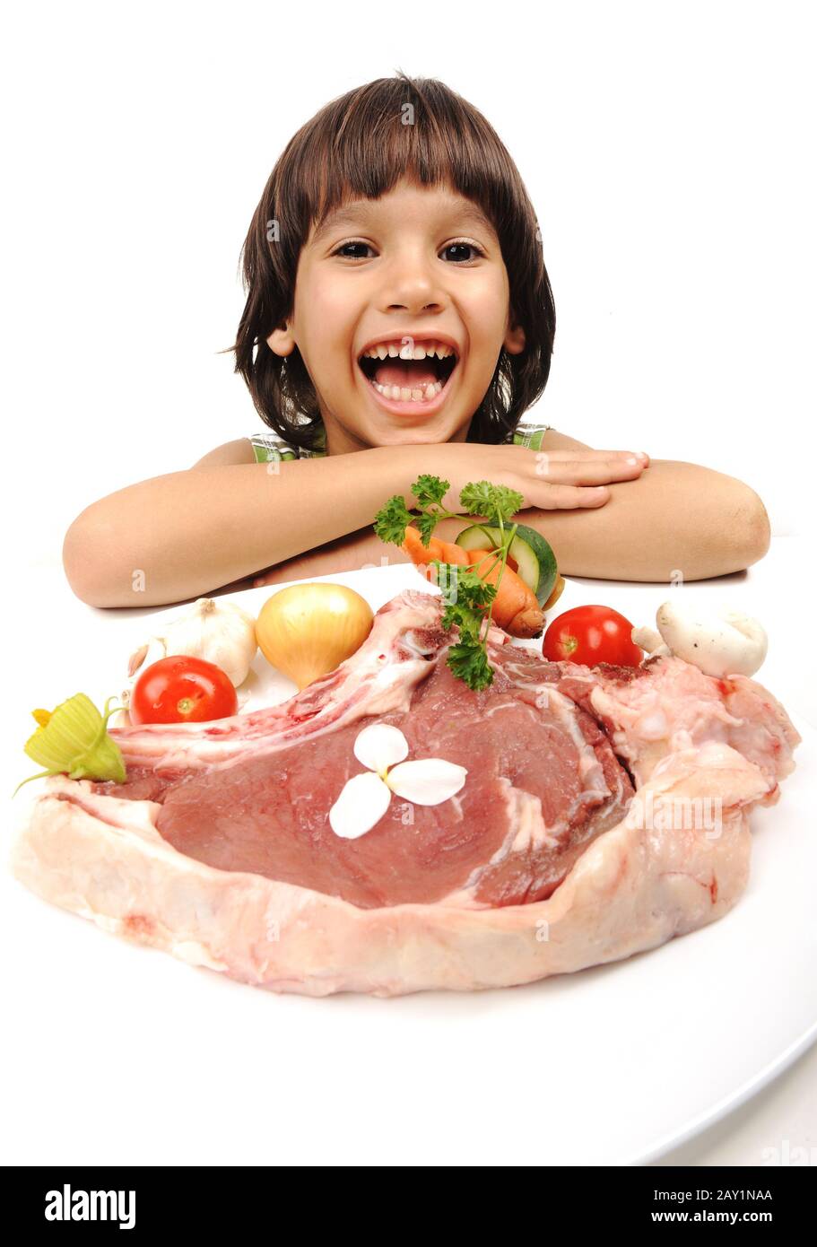 Cute positive boy and raw meat and vegetables in plate reading for ...