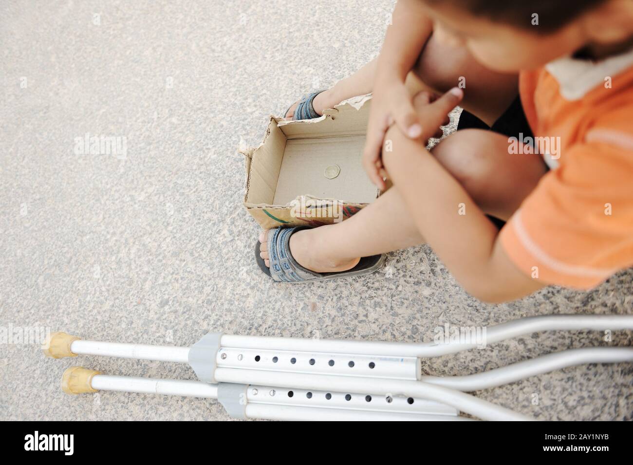 Hungry kid begging on the street with a crutches beside Stock Photo - Alamy