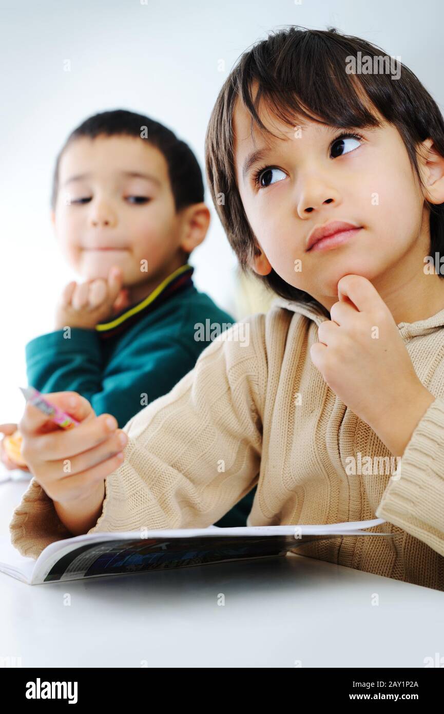 Two cute school boys working on their homework together Stock Photo - Alamy