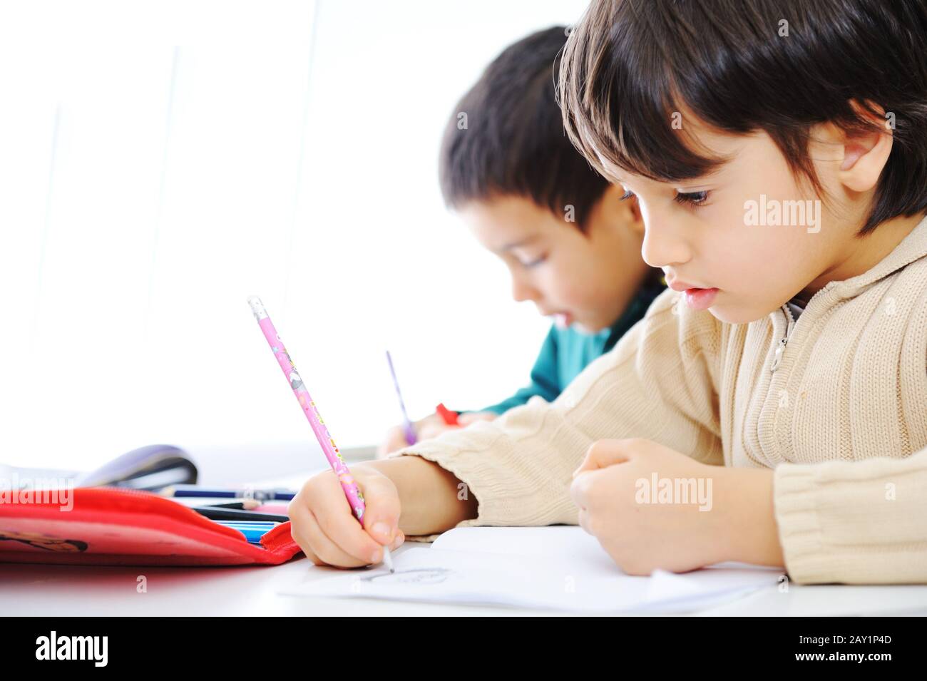 Two cute school boys working on their homework together Stock Photo - Alamy