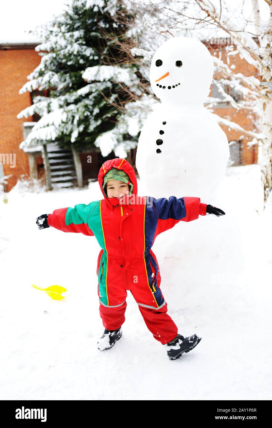 Kid playing happily in snow making snowman, winter season Stock Photo ...