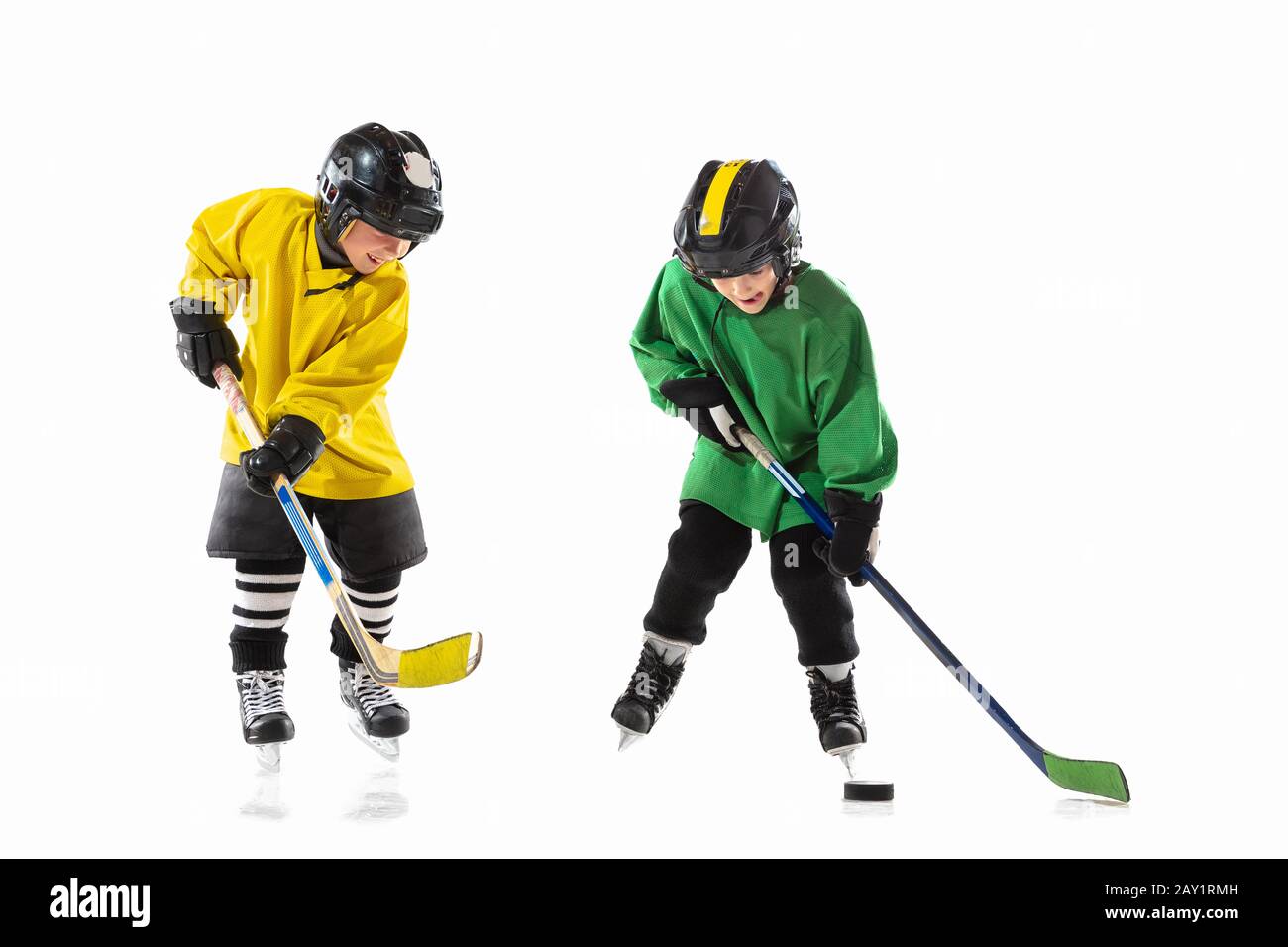 Little hockey players with the sticks on ice court and white studio ...