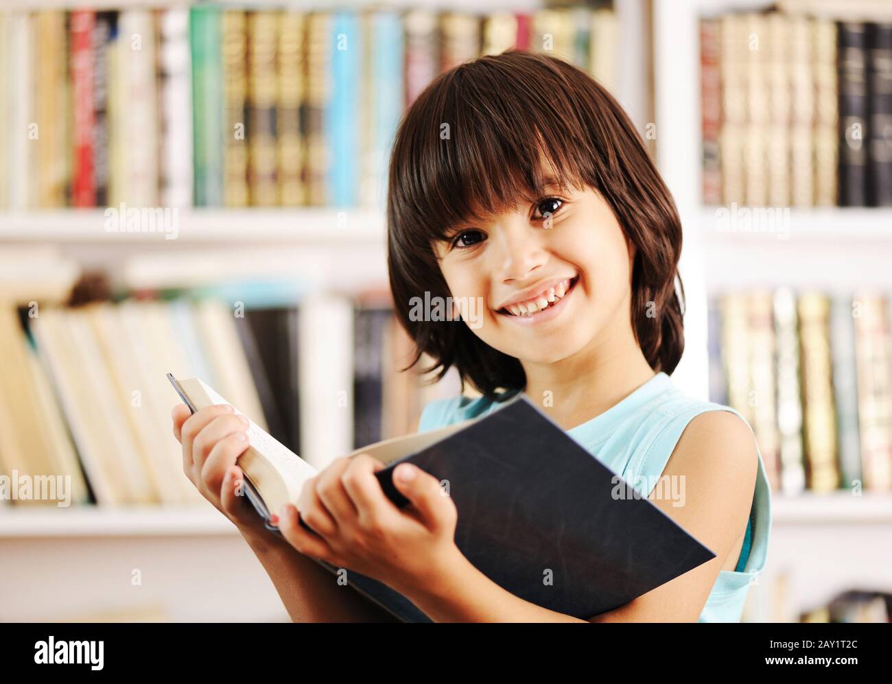 Kid with book in library Stock Photo - Alamy