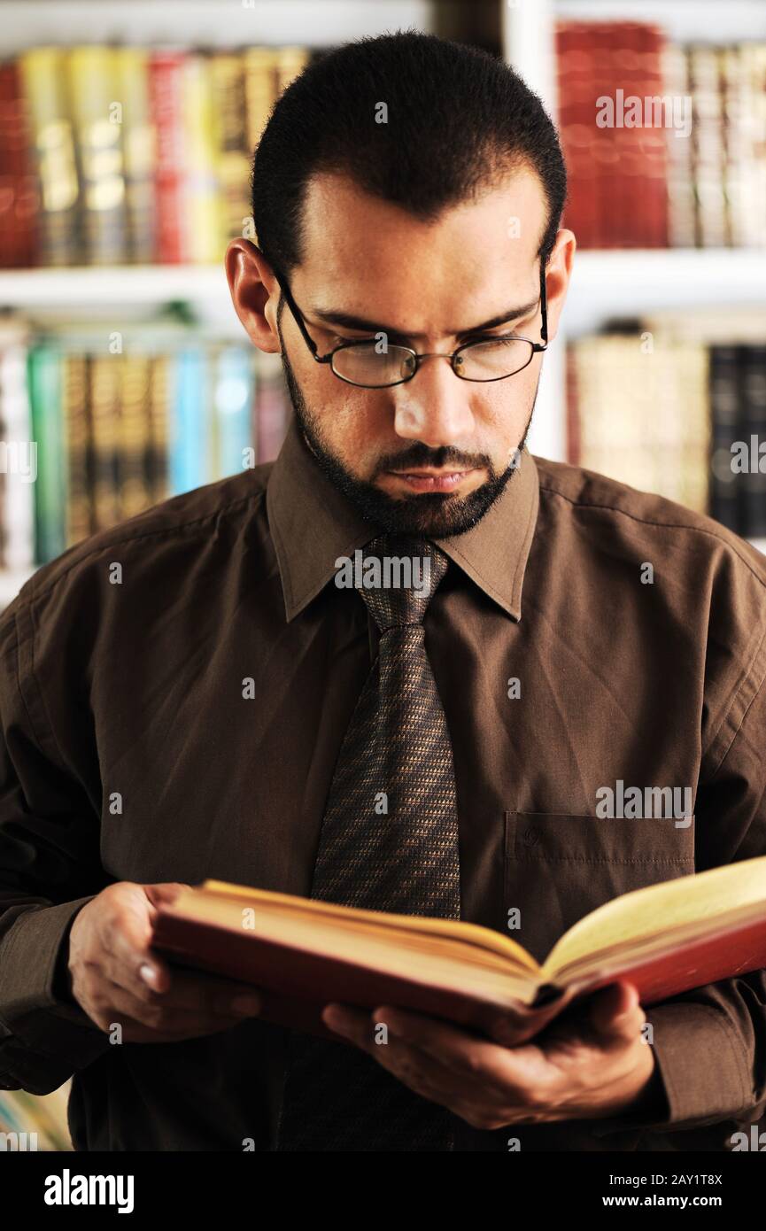 Young man reading book in library Stock Photo - Alamy