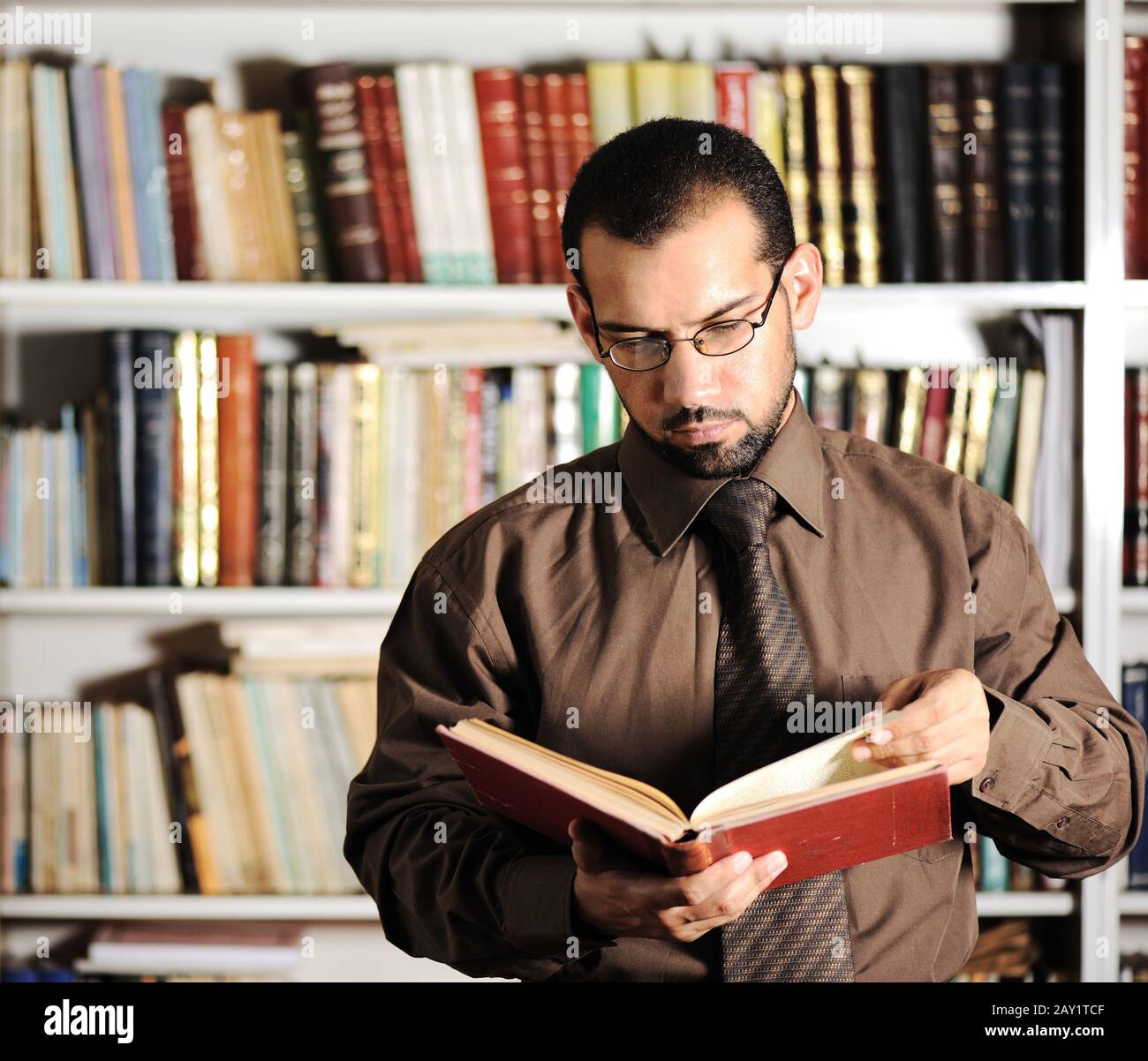 Young man reading book in library Stock Photo - Alamy