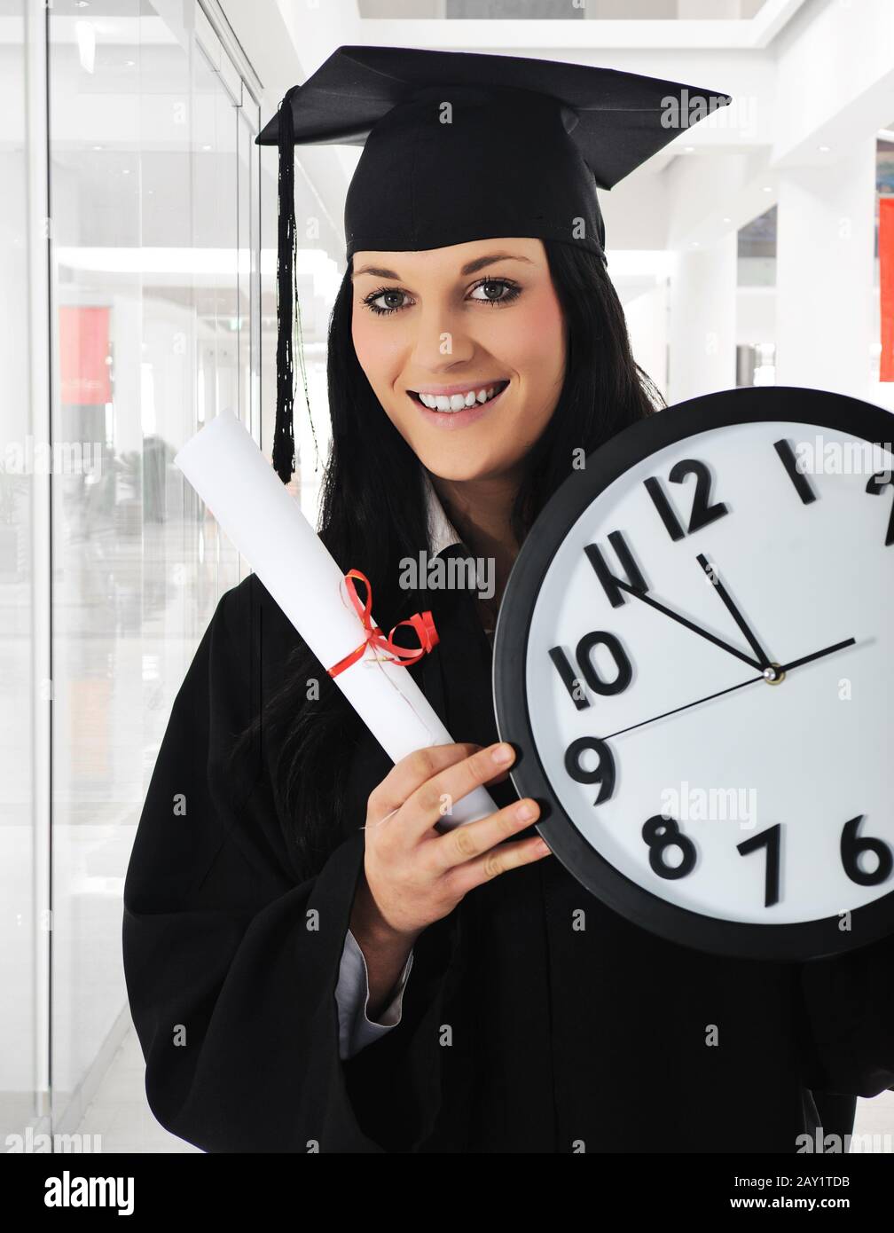 Graduating girl with diploma holding a watch Stock Photo - Alamy