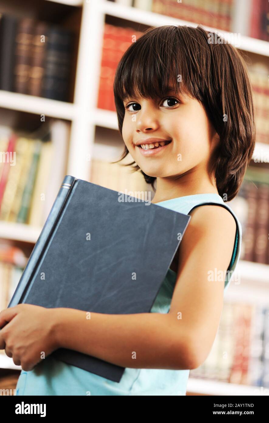 Kid with book in library Stock Photo - Alamy