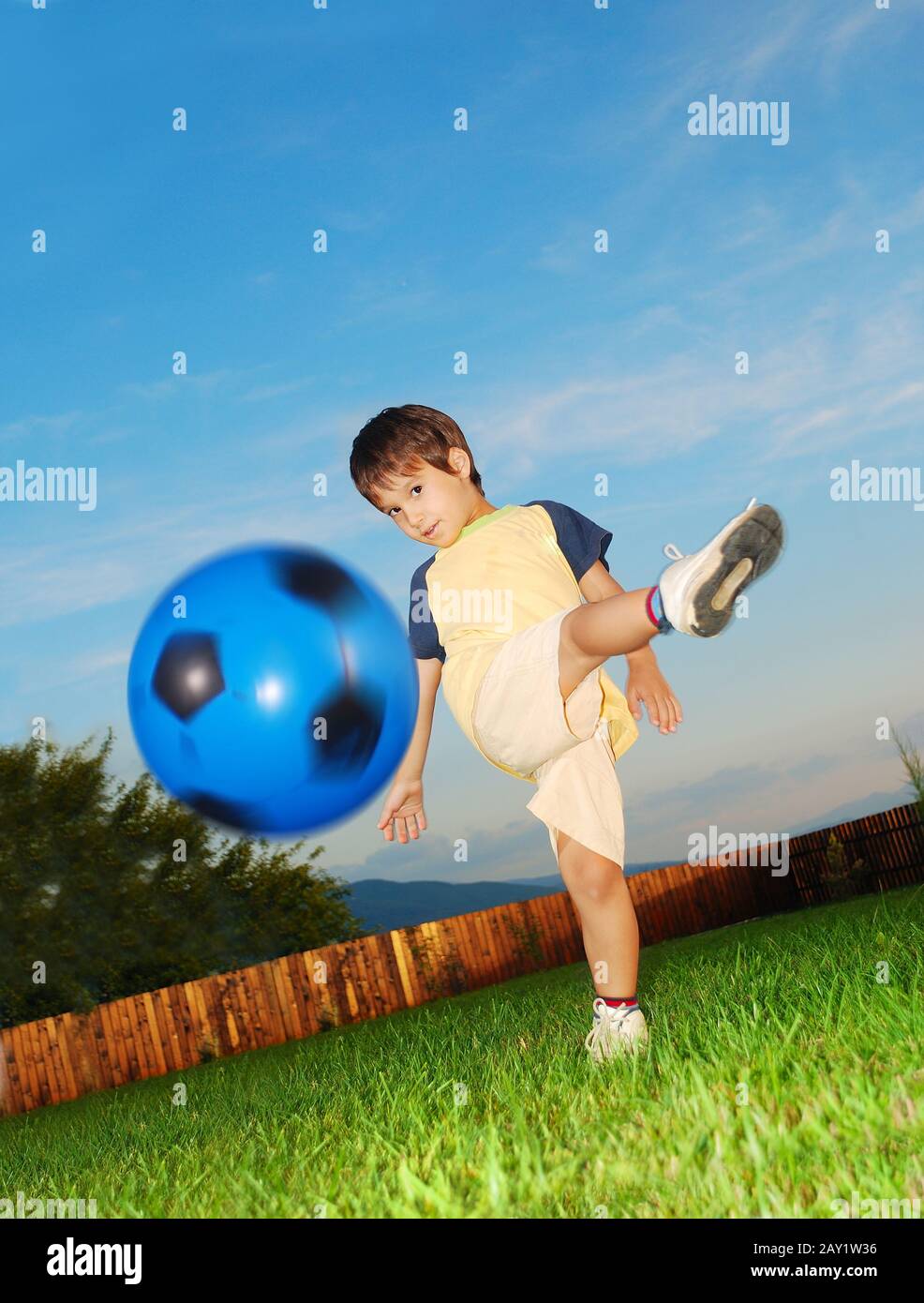Little cute kid is hitting ball by his foot Stock Photo - Alamy